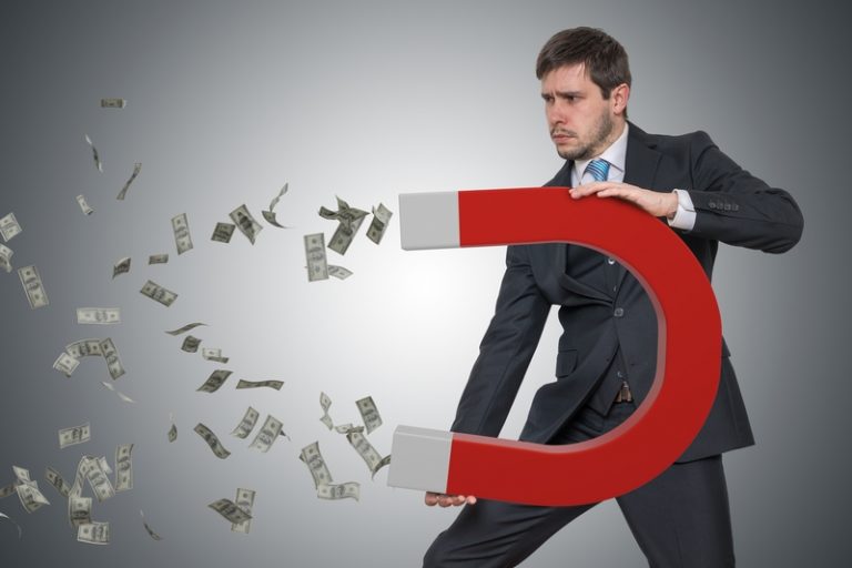 Young businessman is collecting money with big magnet. - Job Crusher